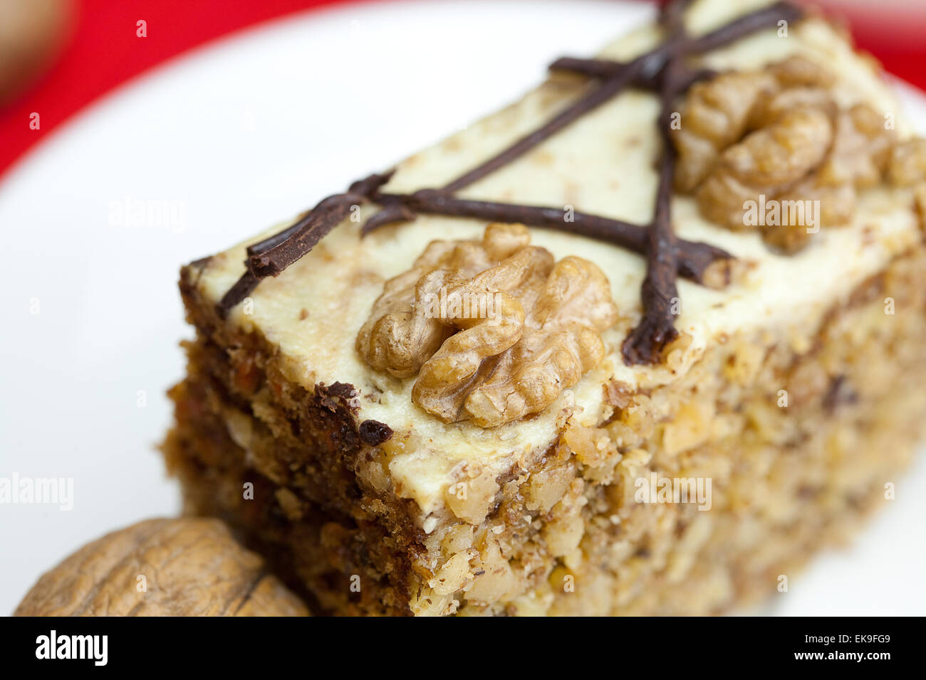 Piece of cake with nuts lying on the plate on a red background Stock ...