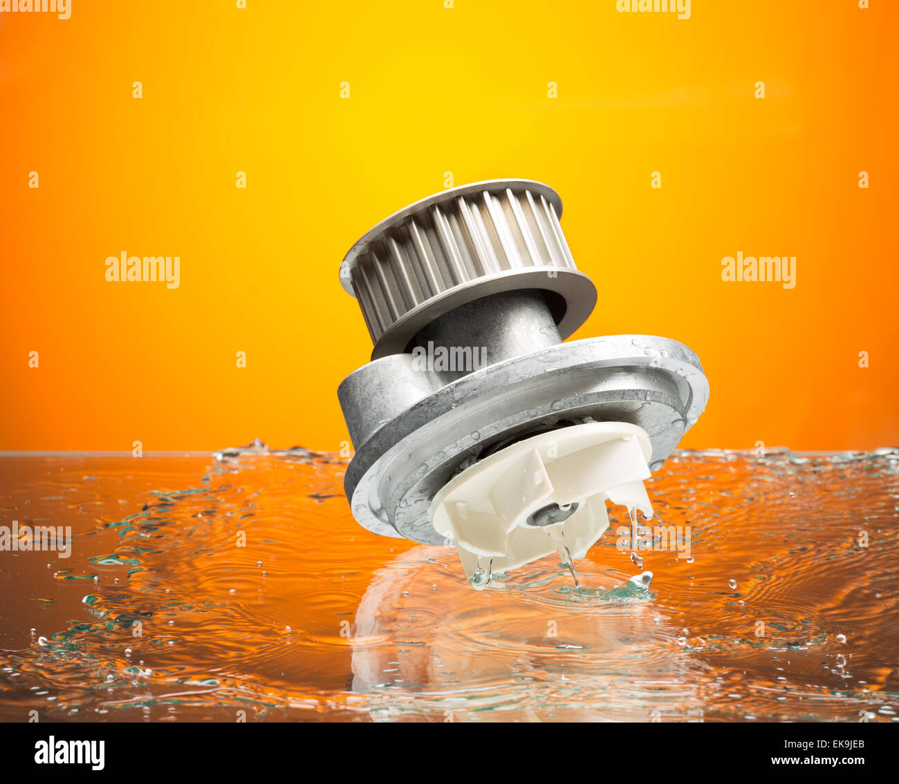 Auto parts, engine cooling pump in water splash on orange gradient ...