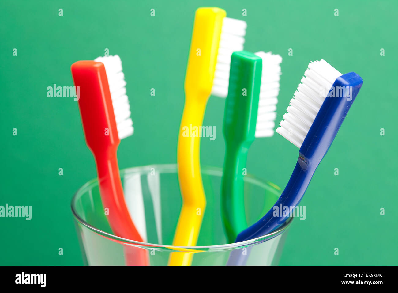 colored toothbrush in a glass on a green background Stock Photo - Alamy