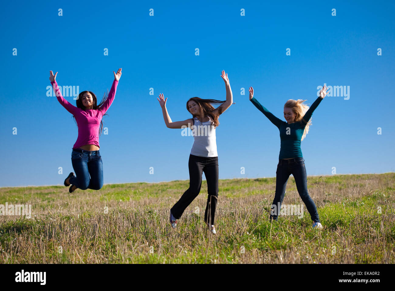 three young beautiful woman jumping into the field against the s Stock ...
