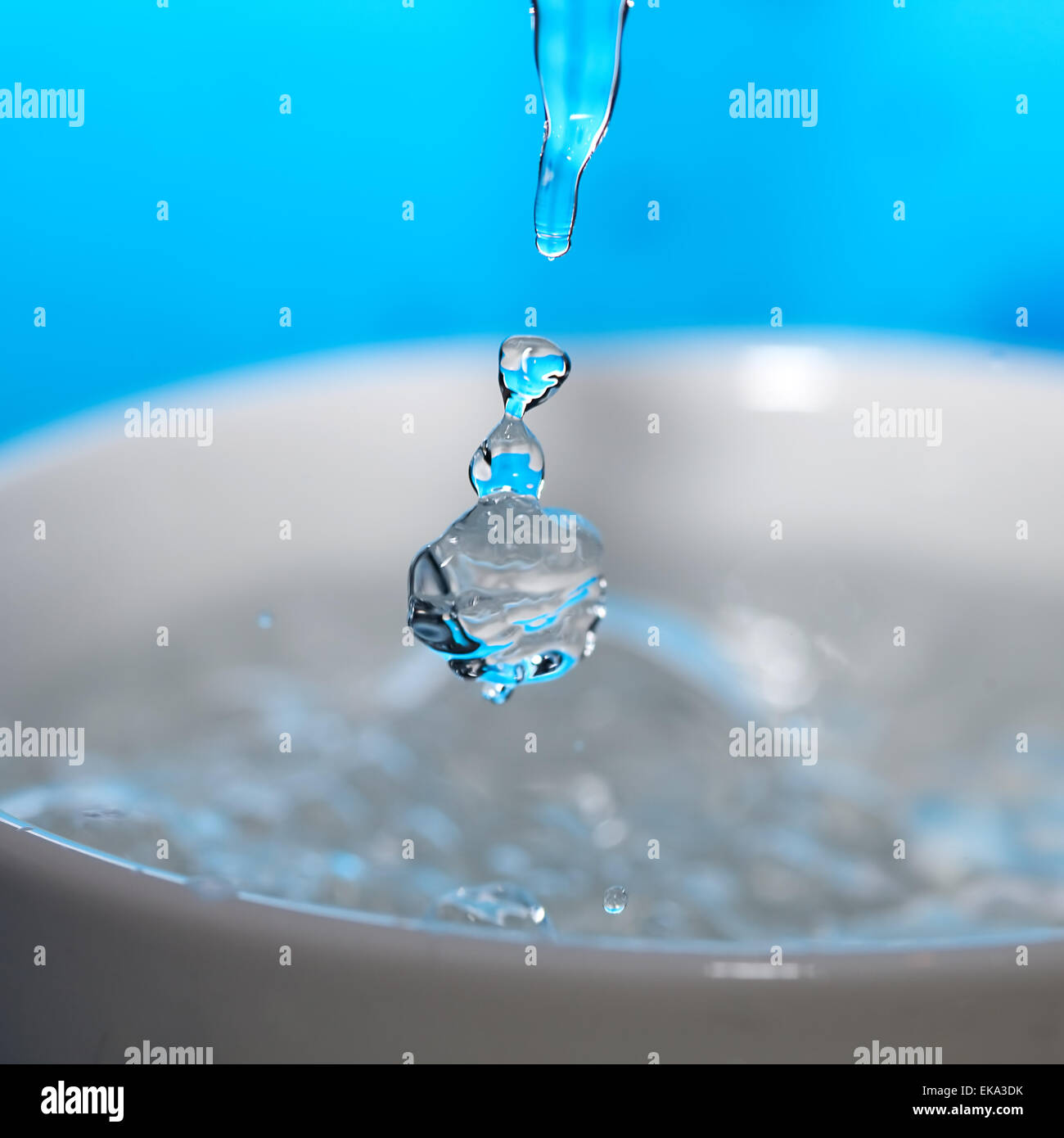 water splash in a cup on a blue background Stock Photo - Alamy