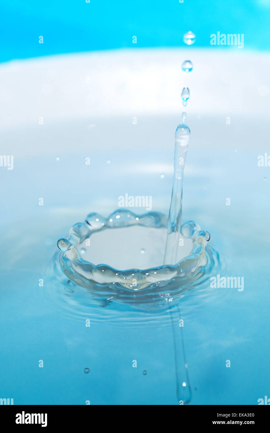 water splash in a cup on a blue background Stock Photo - Alamy