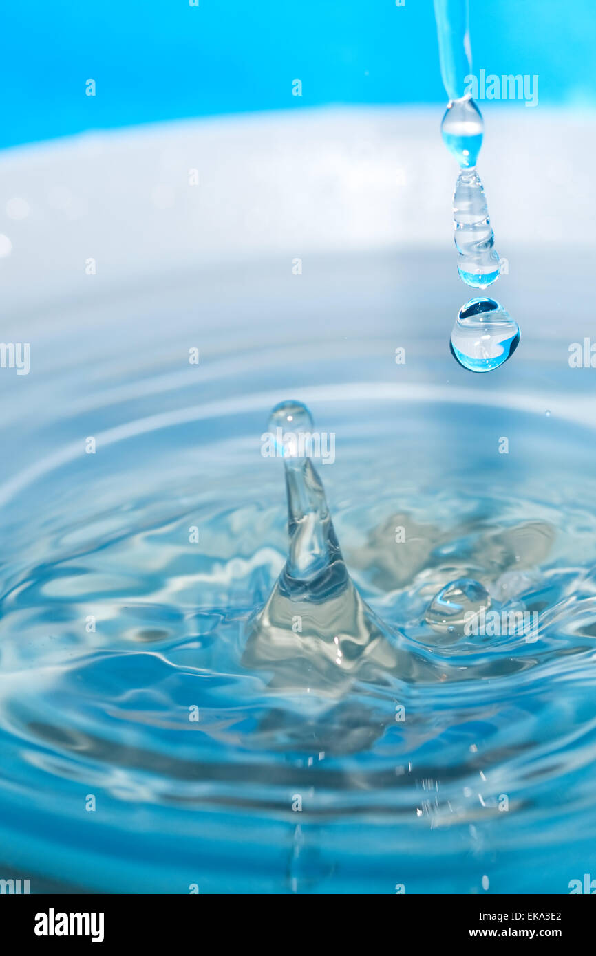water splash in a cup on a blue background Stock Photo - Alamy