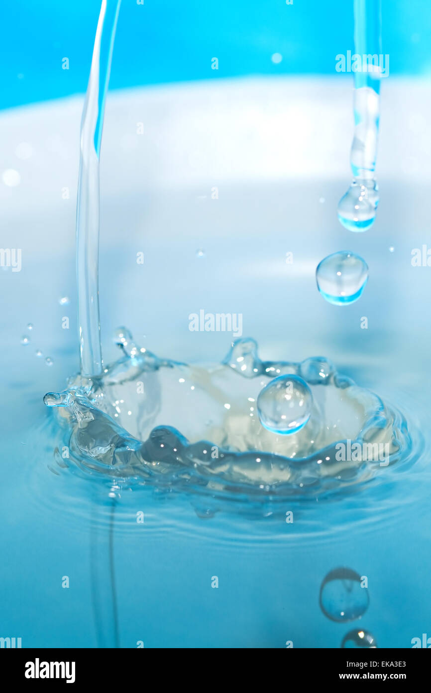 water splash in a cup on a blue background Stock Photo - Alamy