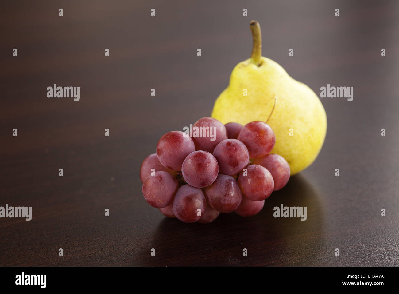 pear and grapes lying on a wooden table Stock Photo - Alamy