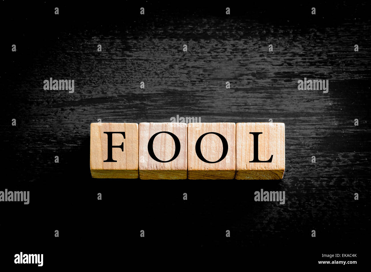 Word FOOL. Wooden small cubes with letters isolated on black background ...