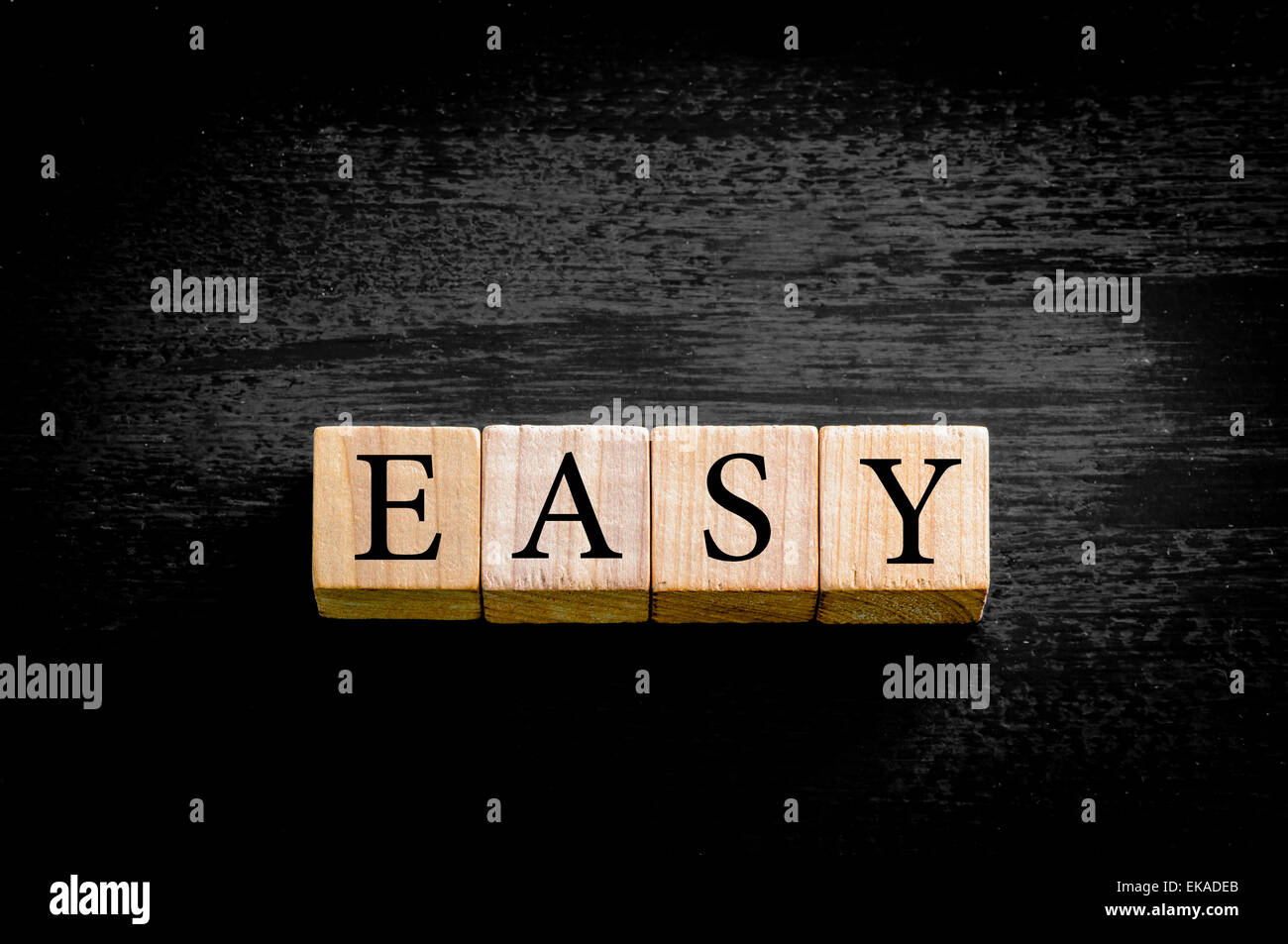 Word EASY. Wooden small cubes with letters isolated on black background ...