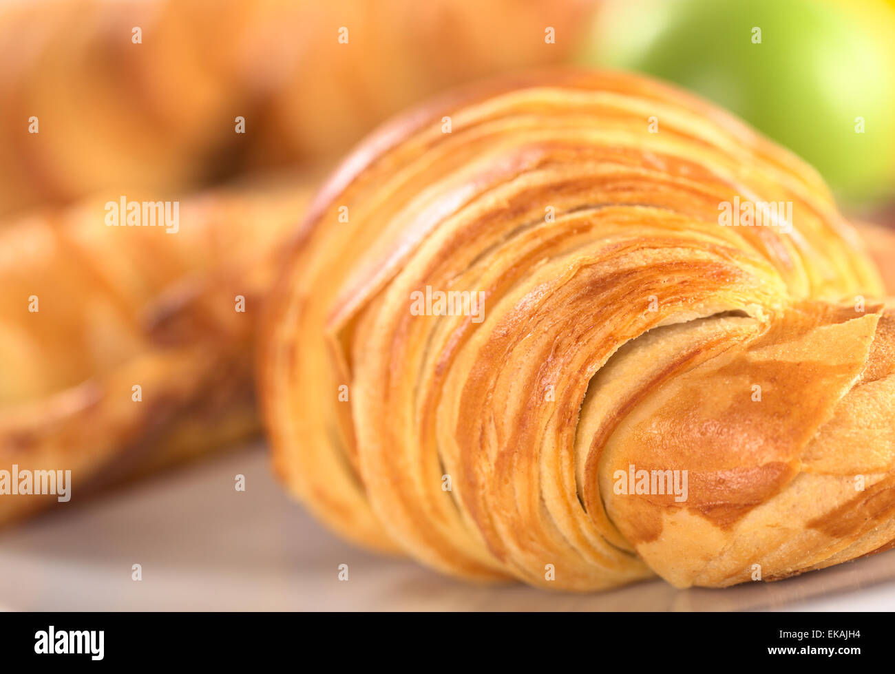 Closeup of a croissant with a green apple in the background (Selective ...