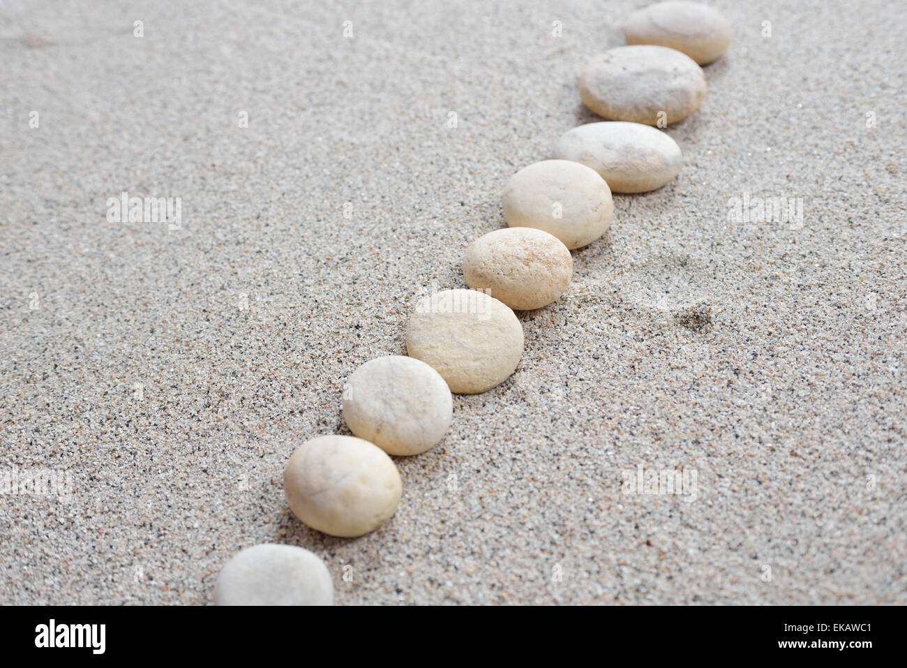Few stones arranged on beach sand with a bright background Stock Photo ...