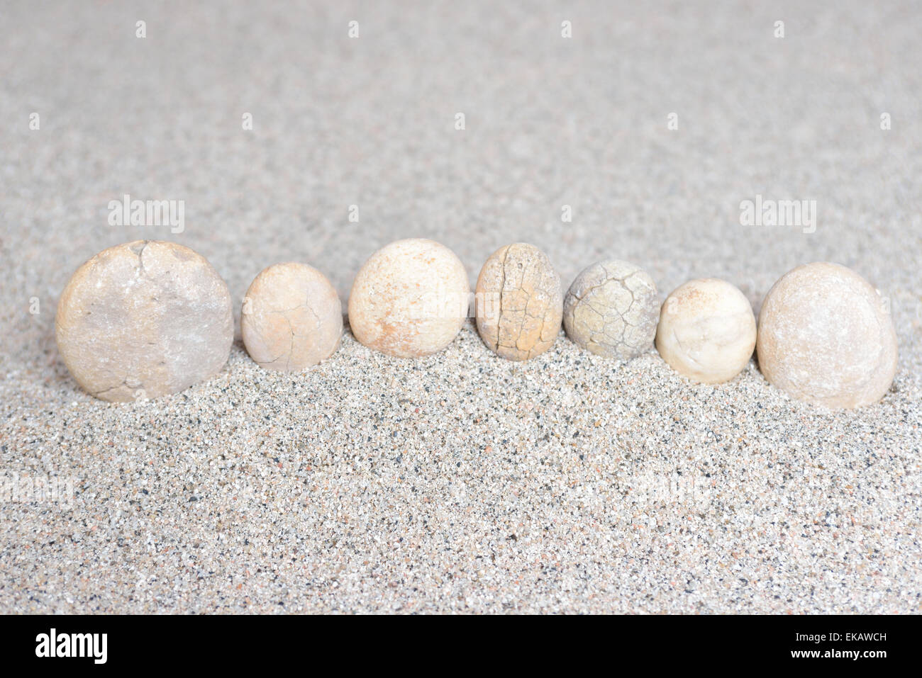 Few stones arranged on beach sand with a bright background Stock Photo ...