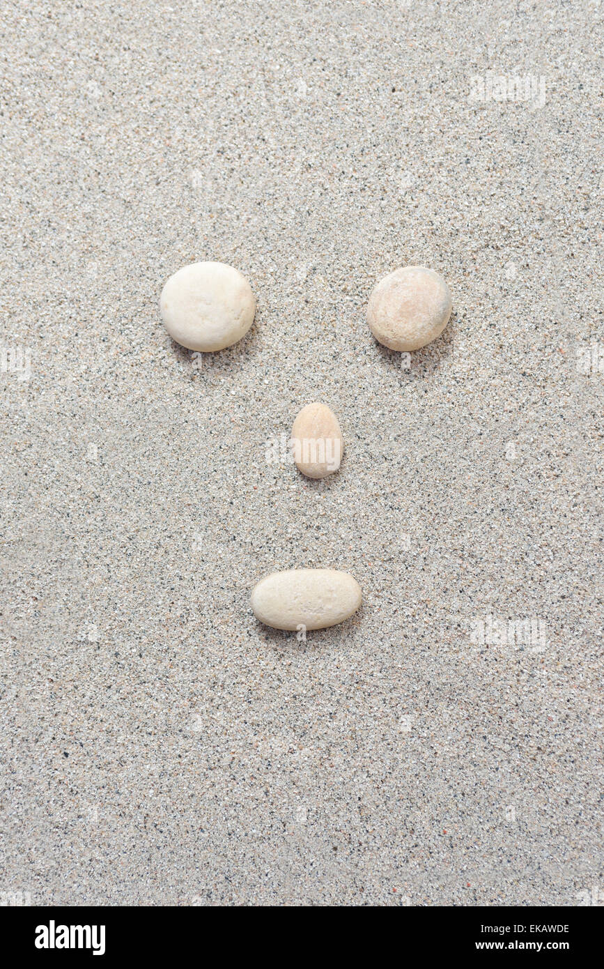 Pebble smiling isolated on a sand background Stock Photo - Alamy