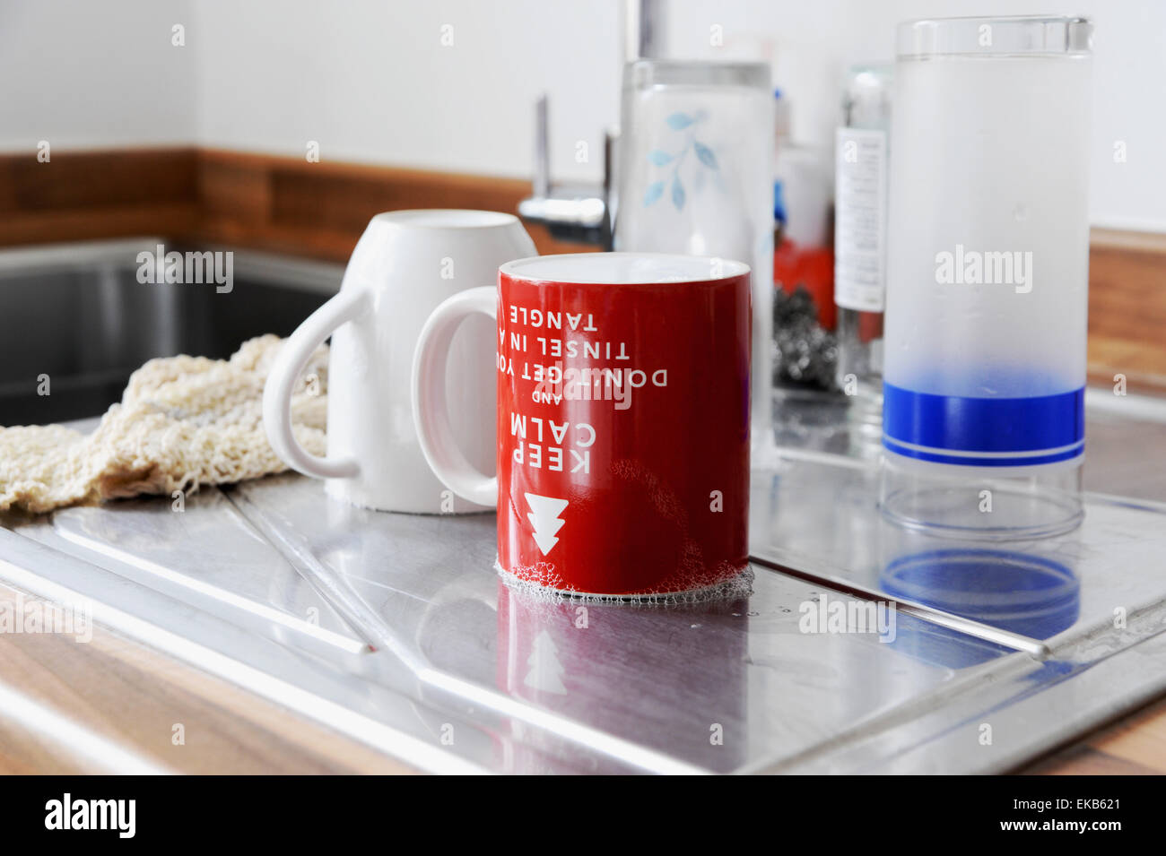 Cups mugs and glasses draining at washing up sink in a domestic kitchen ...