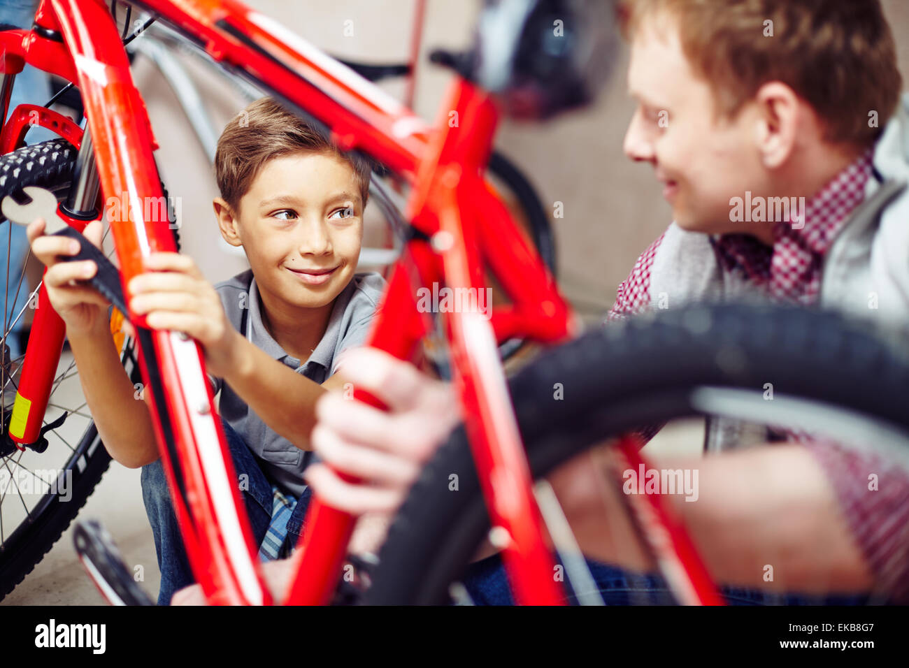 Happy lad looking at his father while helping him in garage Stock Photo ...