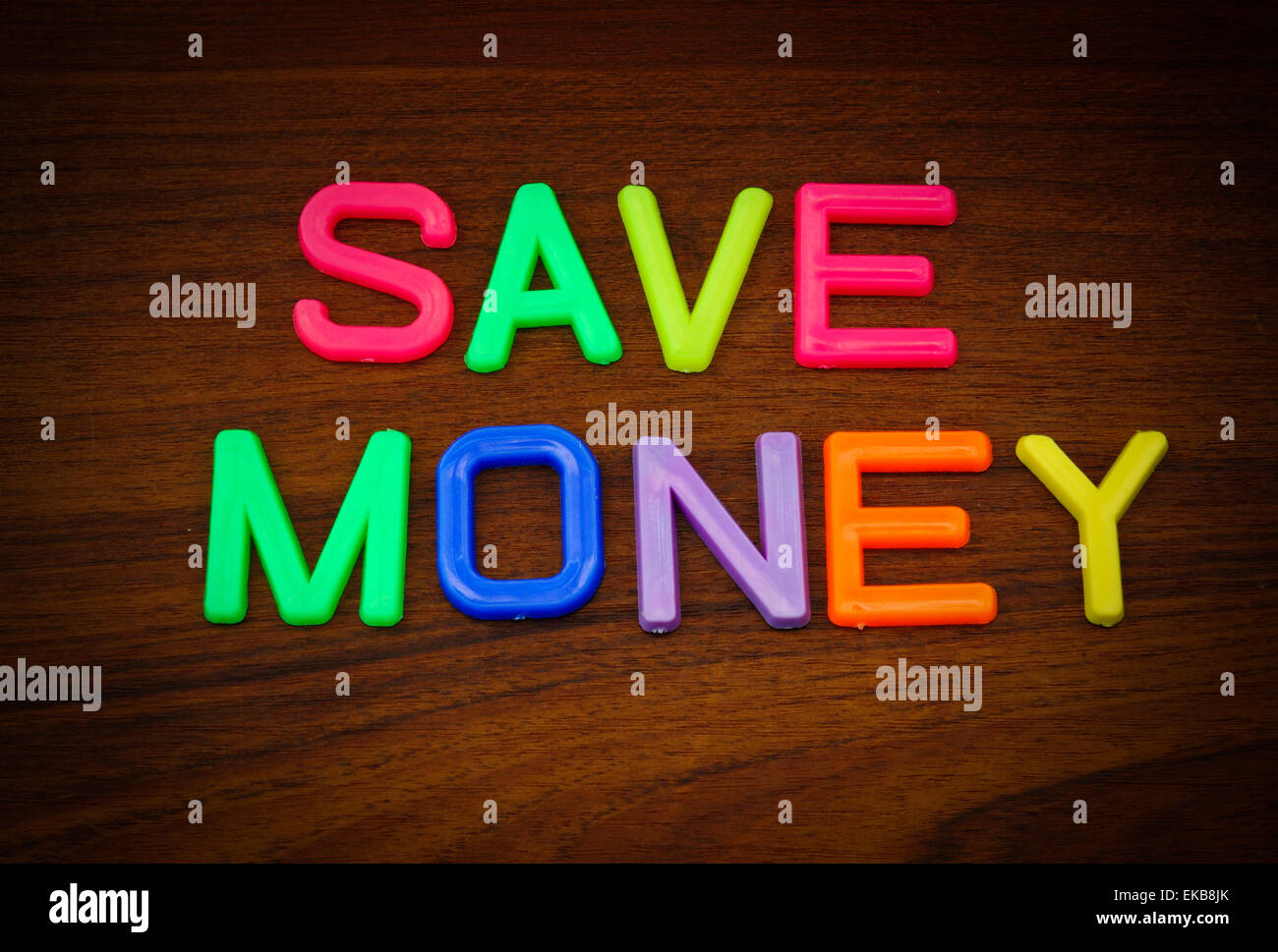 Save money in colorful toy letters on wood background Stock Photo - Alamy