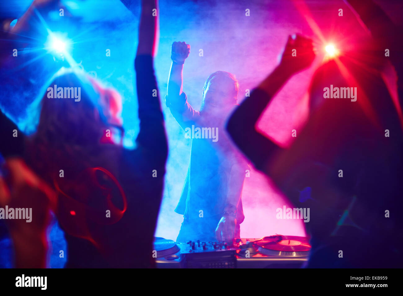 Excited deejay and dancing crowd enjoying disco party in nightclub ...