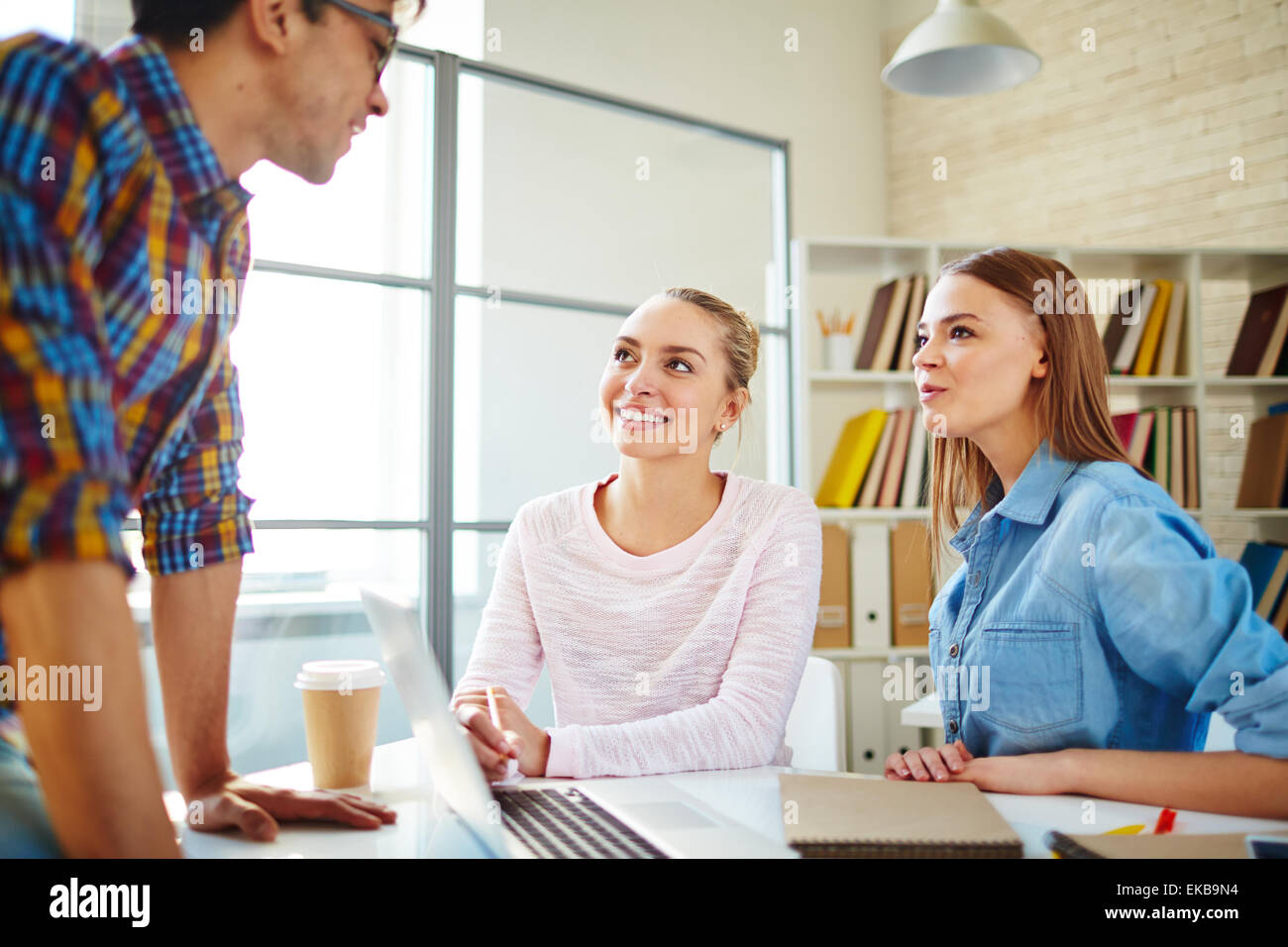 Two cute teenage girls looking at their groupmate Stock Photo - Alamy