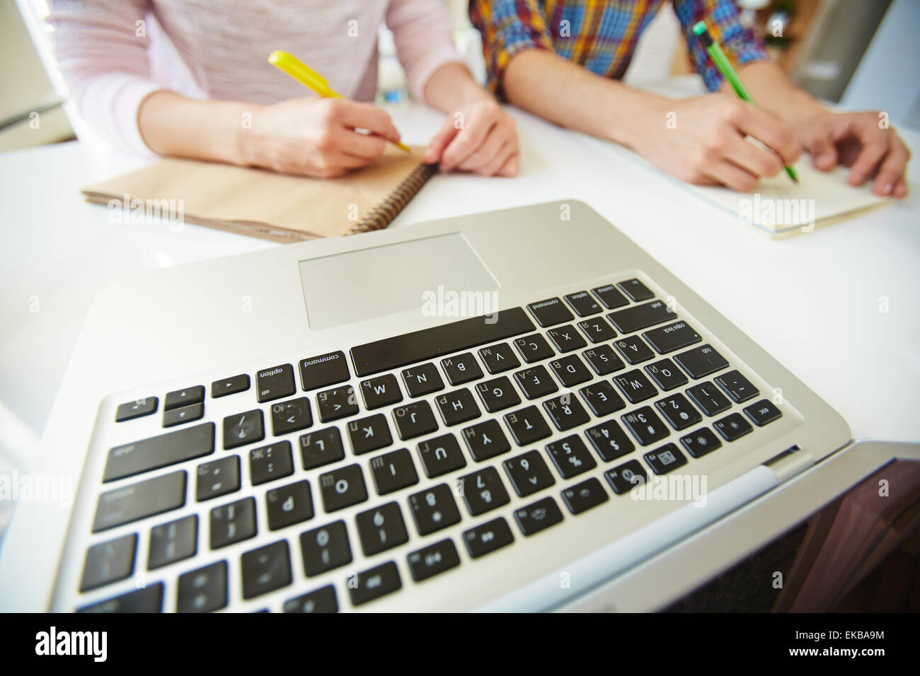 Laptop keypad at workplace on background of two girls making notes ...