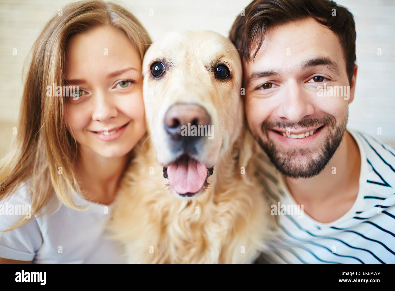 Happy young couple and their pet looking at camera Stock Photo - Alamy