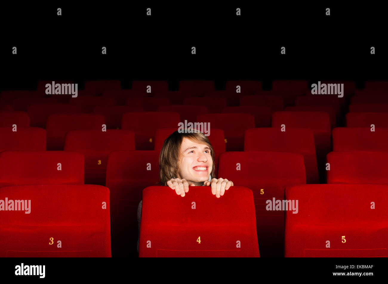 young man in the cinema hiding behind a chair Stock Photo - Alamy