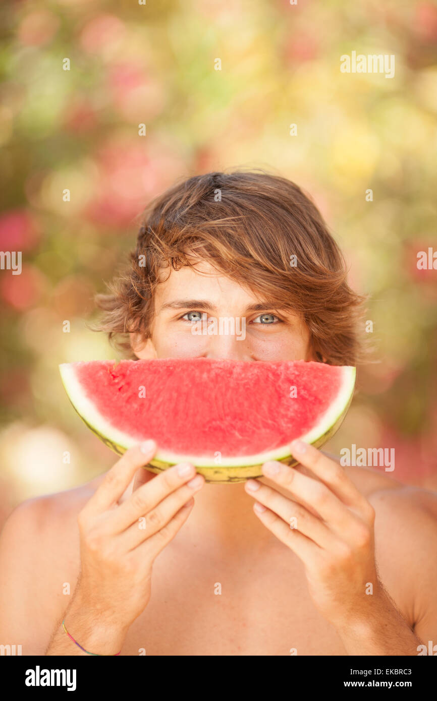 Portrait of a beautiful young man eating watermelon Stock Photo - Alamy
