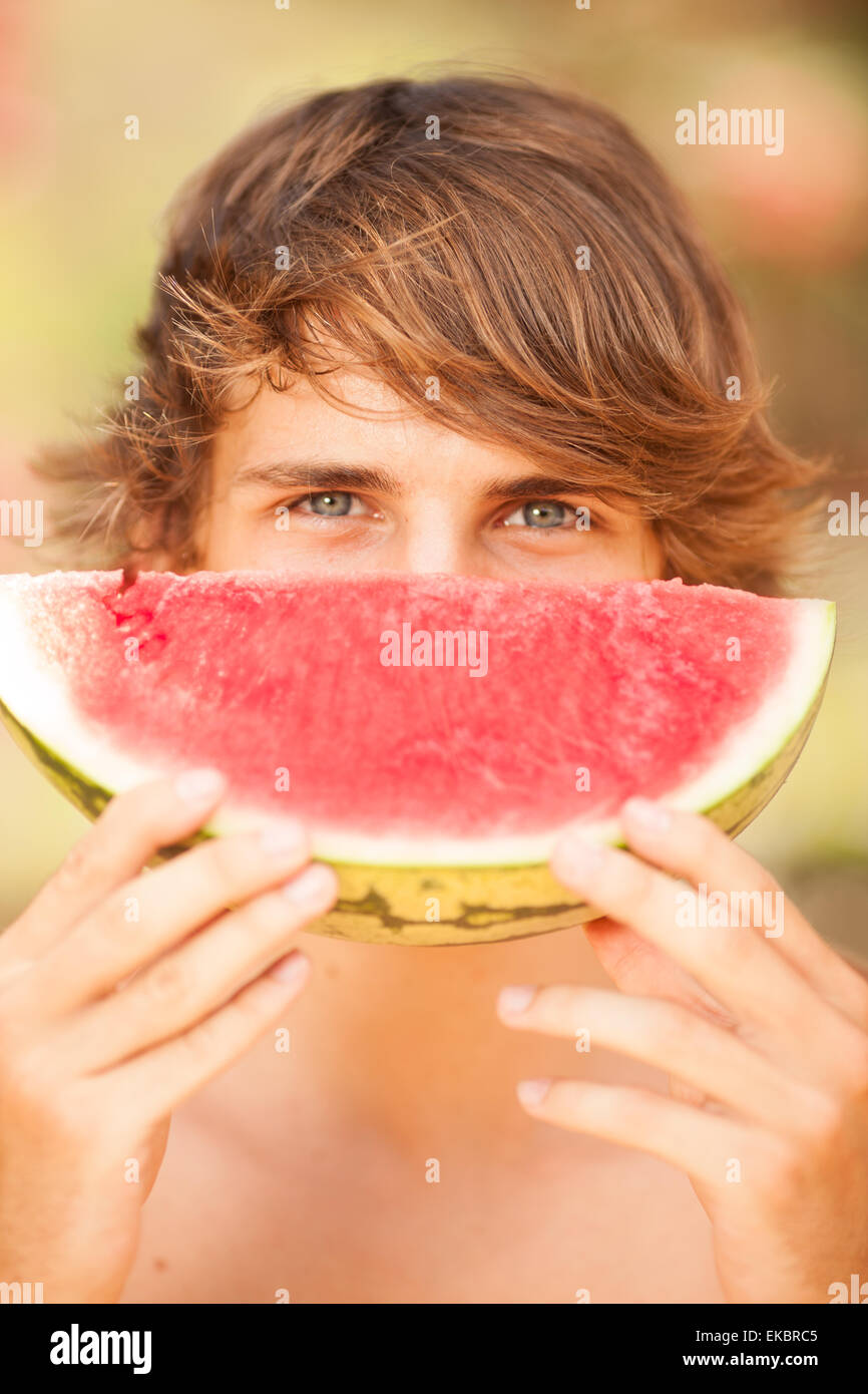 Portrait of a beautiful young man eating watermelon Stock Photo - Alamy