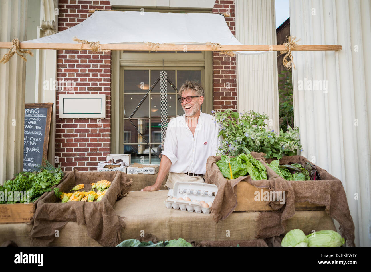 Farmer selling organic eggs and vegetables on stall outside store Stock ...