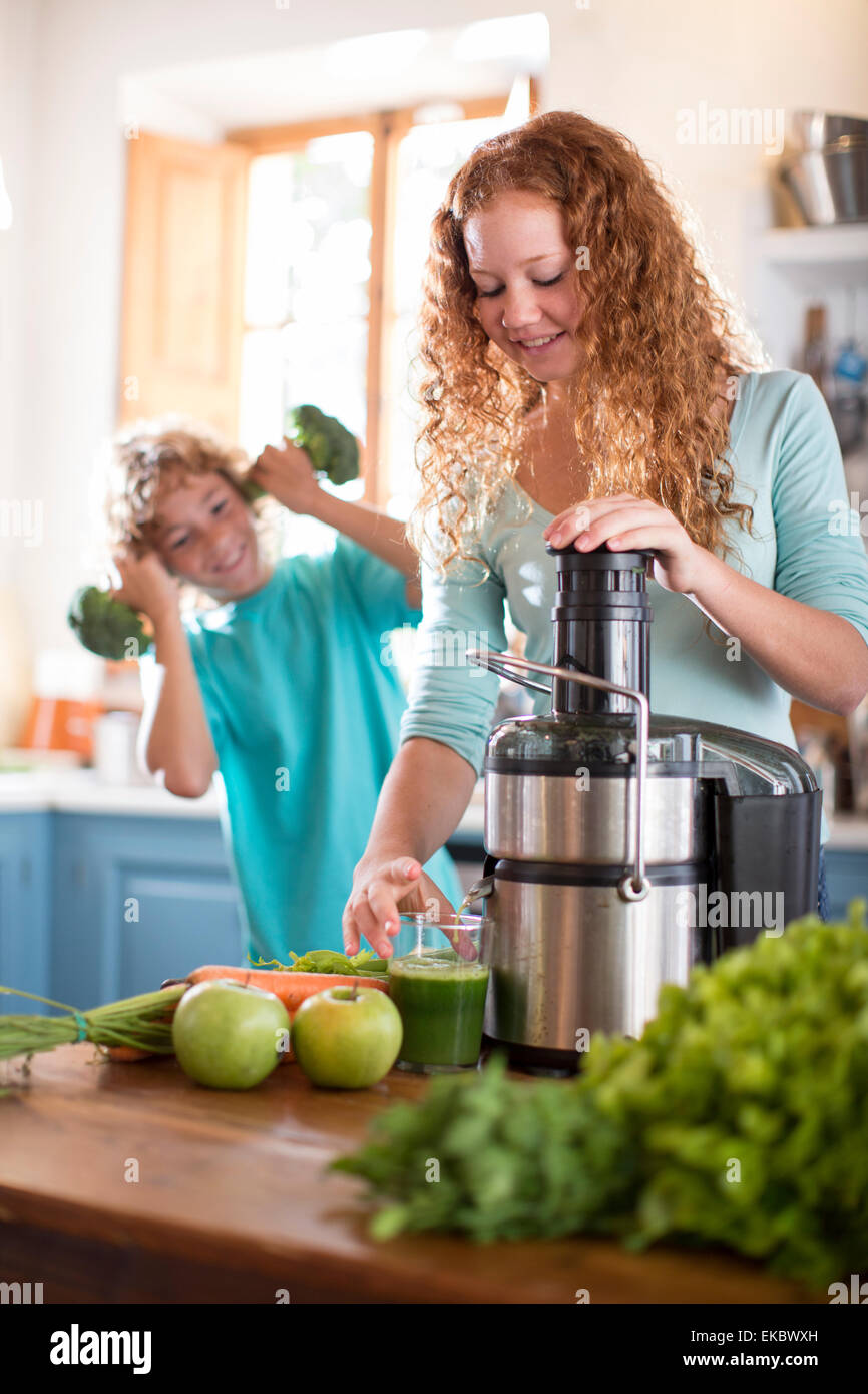 Sister blending fruit, brother playing with broccoli in background ...