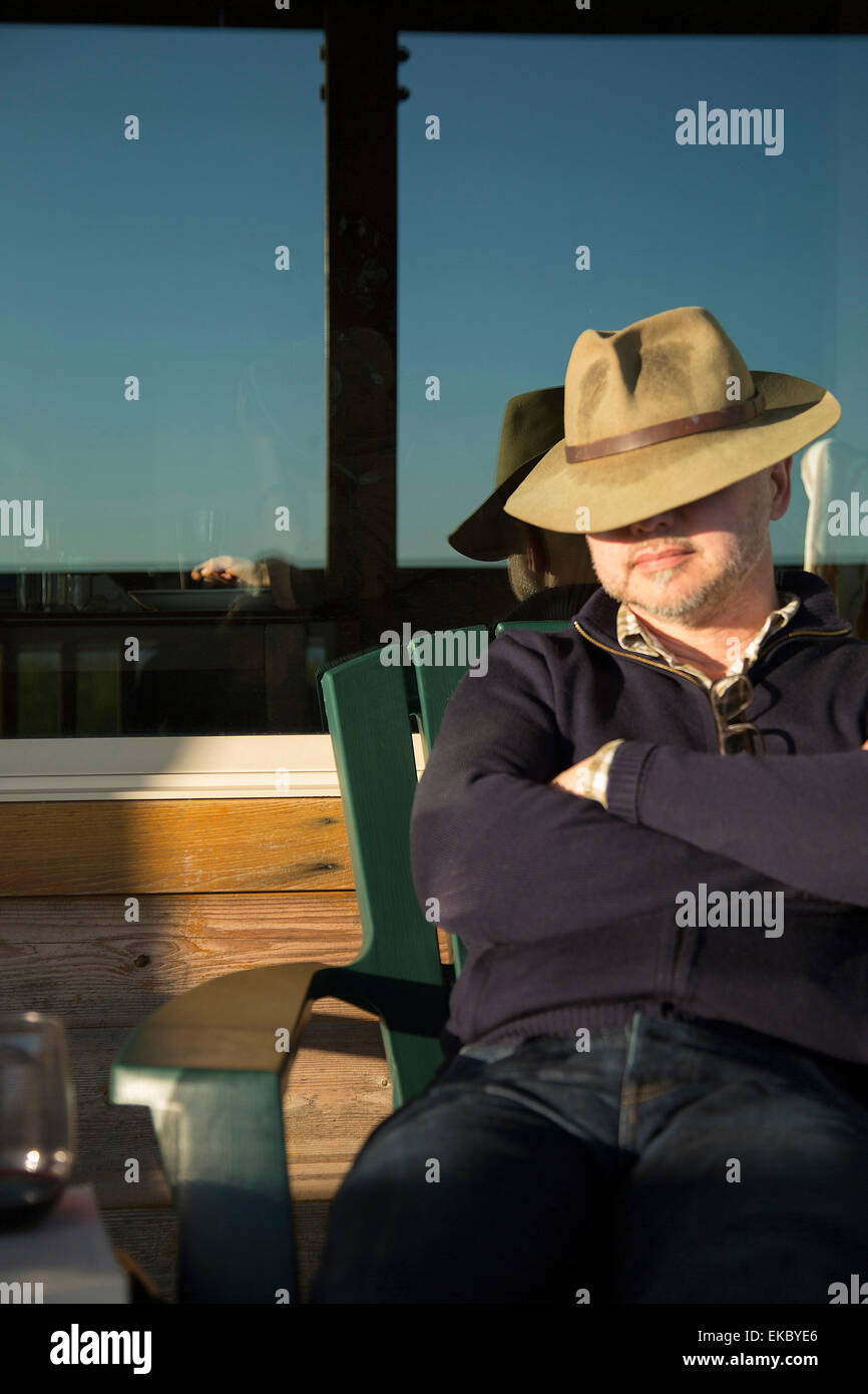 Man snoozing on chair with hat over eyes Stock Photo - Alamy