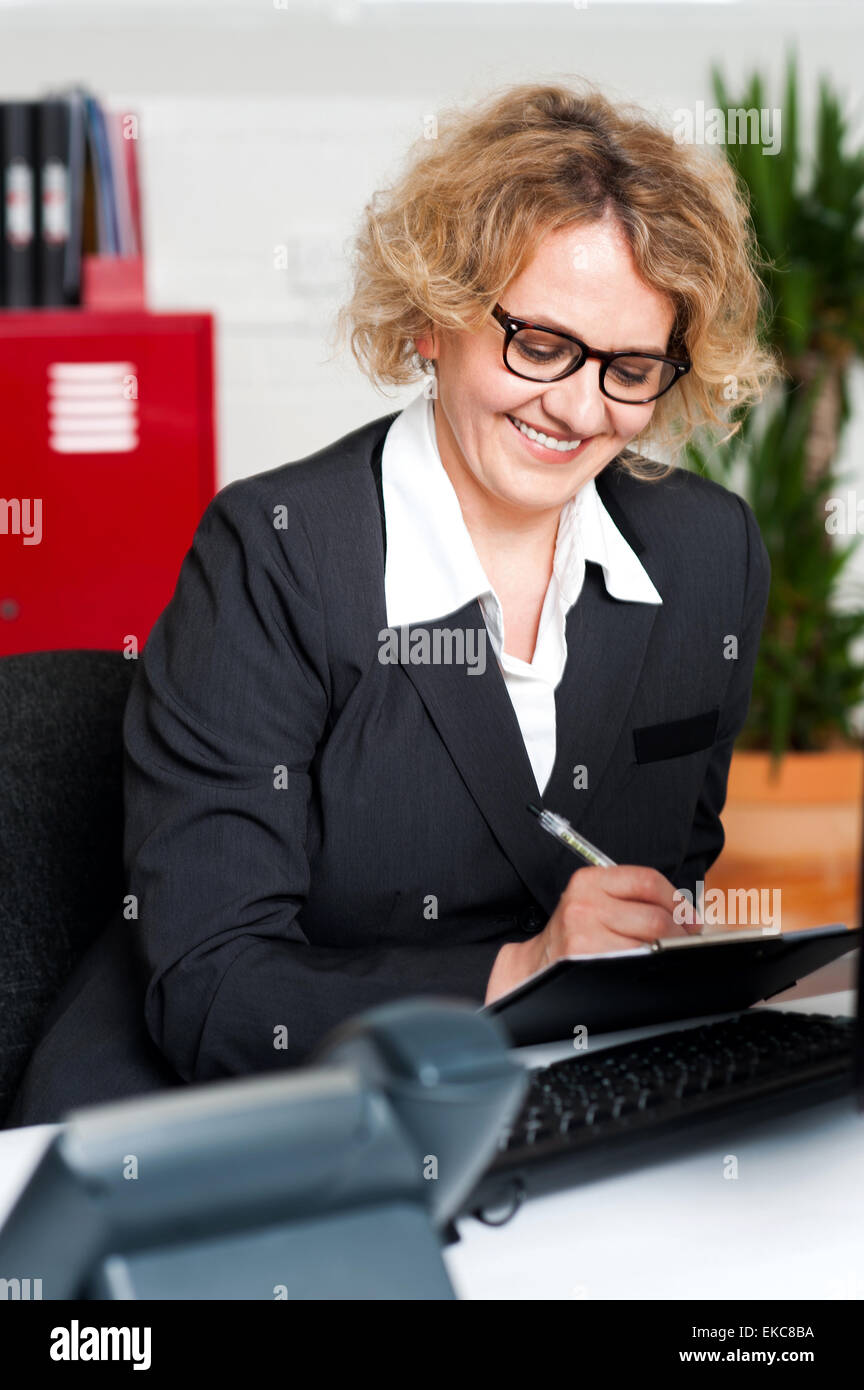 Cheerful office worker writing notes Stock Photo - Alamy