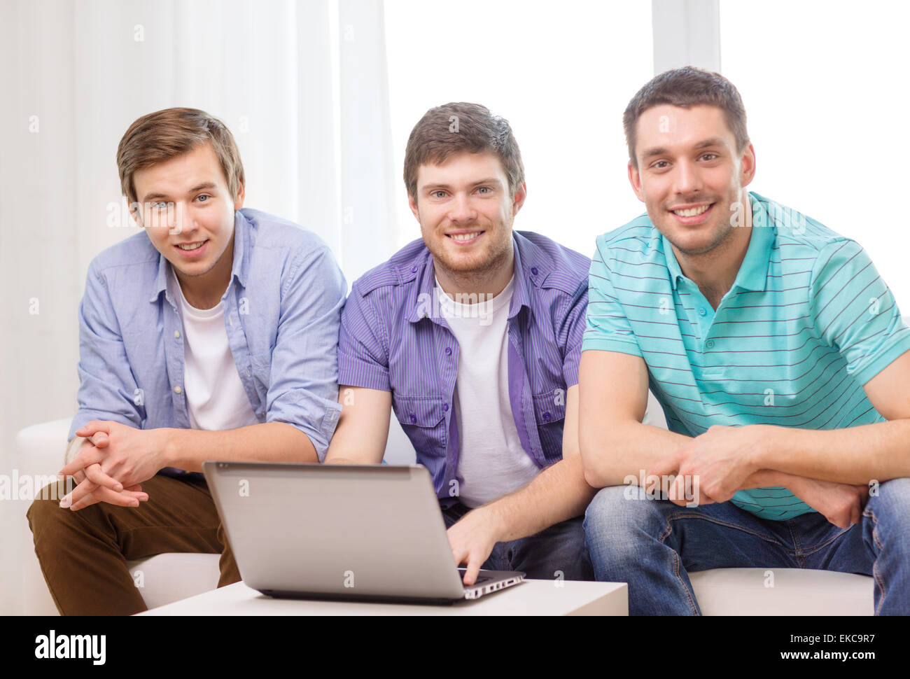 smiling friends with laptop computer at home Stock Photo - Alamy