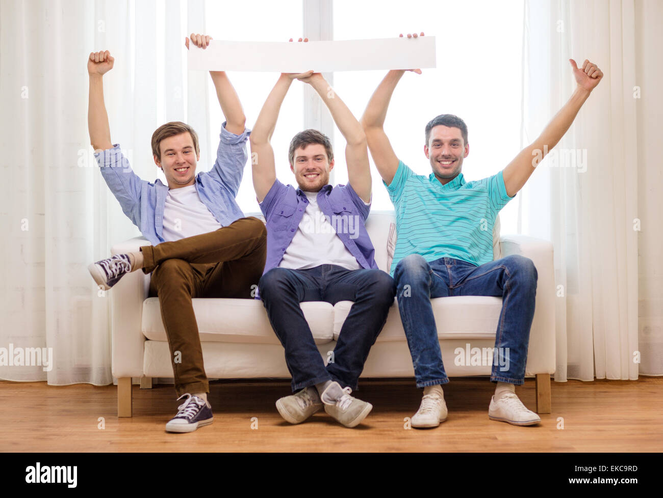 smiling male friends holding white blank banner Stock Photo - Alamy