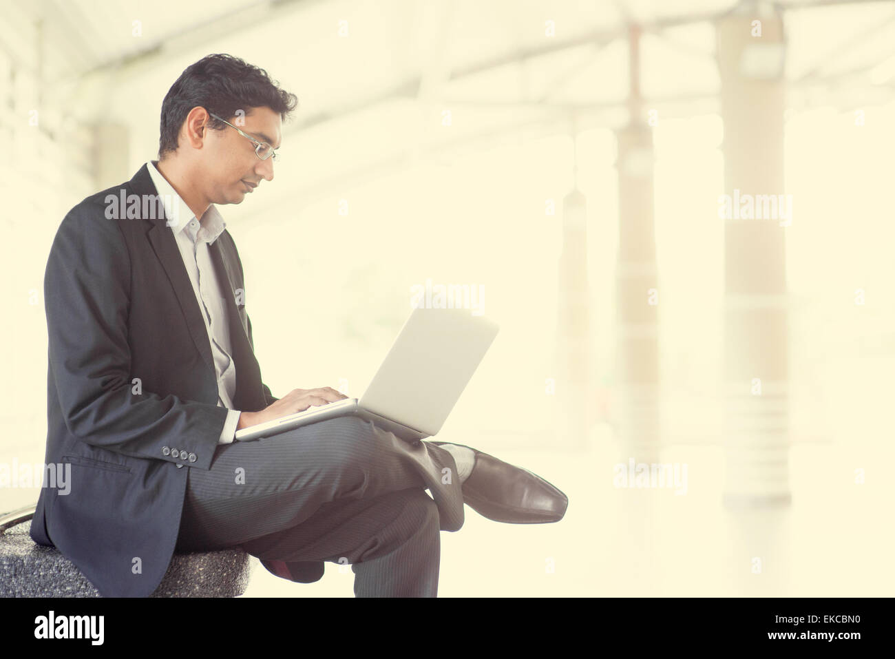Asian Indian businessman using laptop computer while waiting train at ...