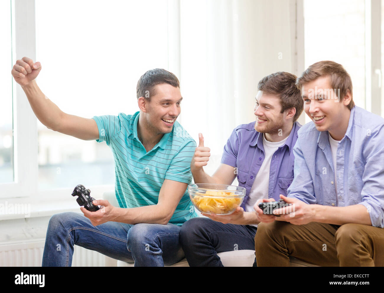 smiling friends playing video games at home Stock Photo - Alamy