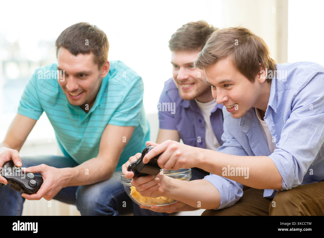 smiling friends playing video games at home Stock Photo - Alamy
