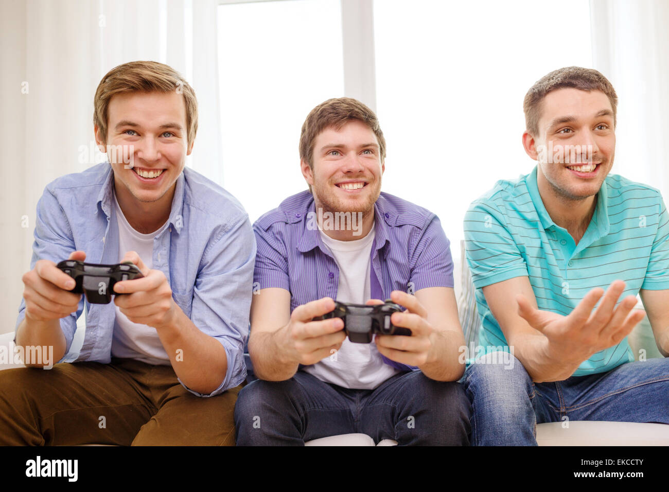 smiling friends playing video games at home Stock Photo - Alamy