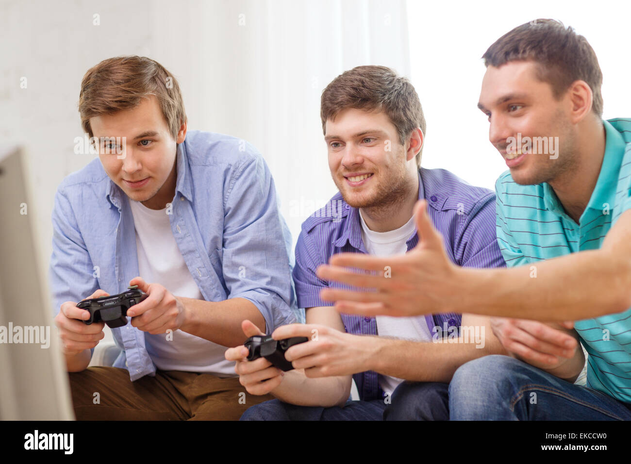 smiling friends playing video games at home Stock Photo - Alamy