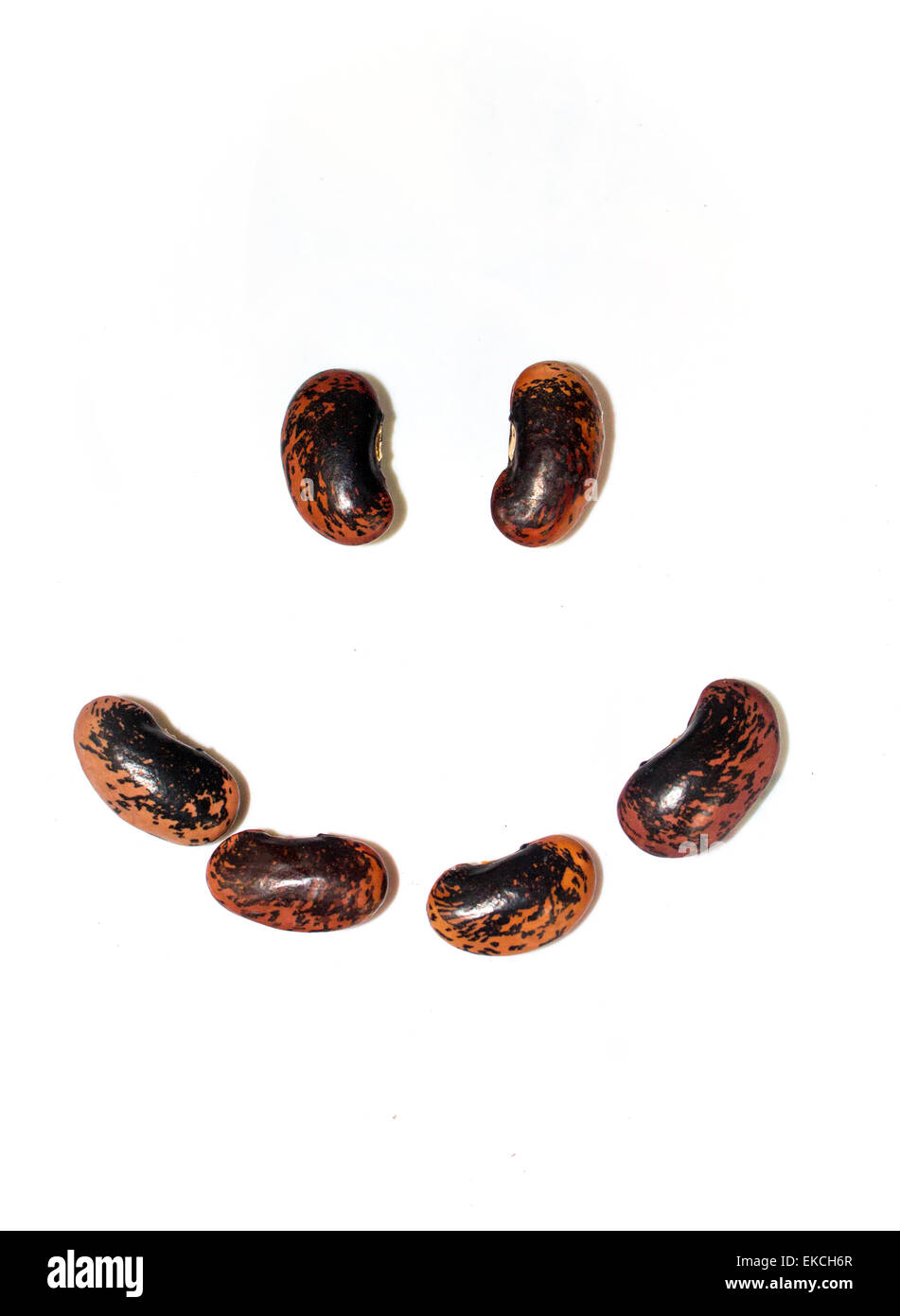 Runner bean seeds in the shape of a smiley face on a plain white ...