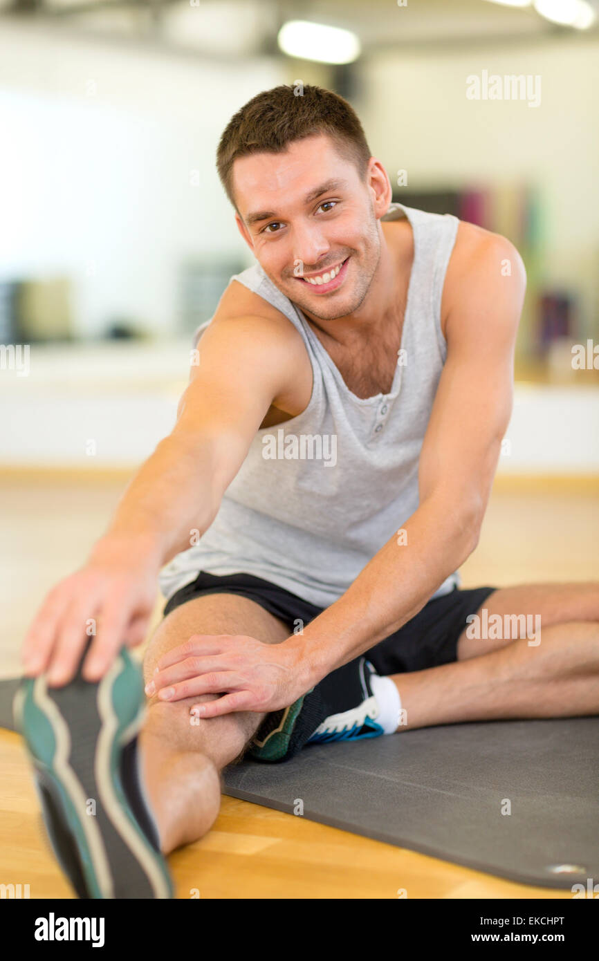 smiling man stretching on mat in the gym Stock Photo - Alamy
