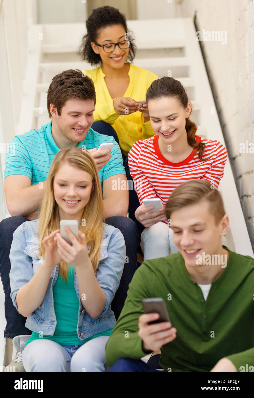 smiling students with smartphone texting at school Stock Photo - Alamy