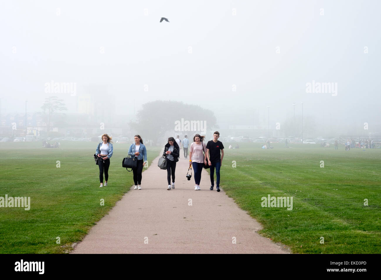 young people enjoy a walk as a heavy sea mist drifts in from the sea ...