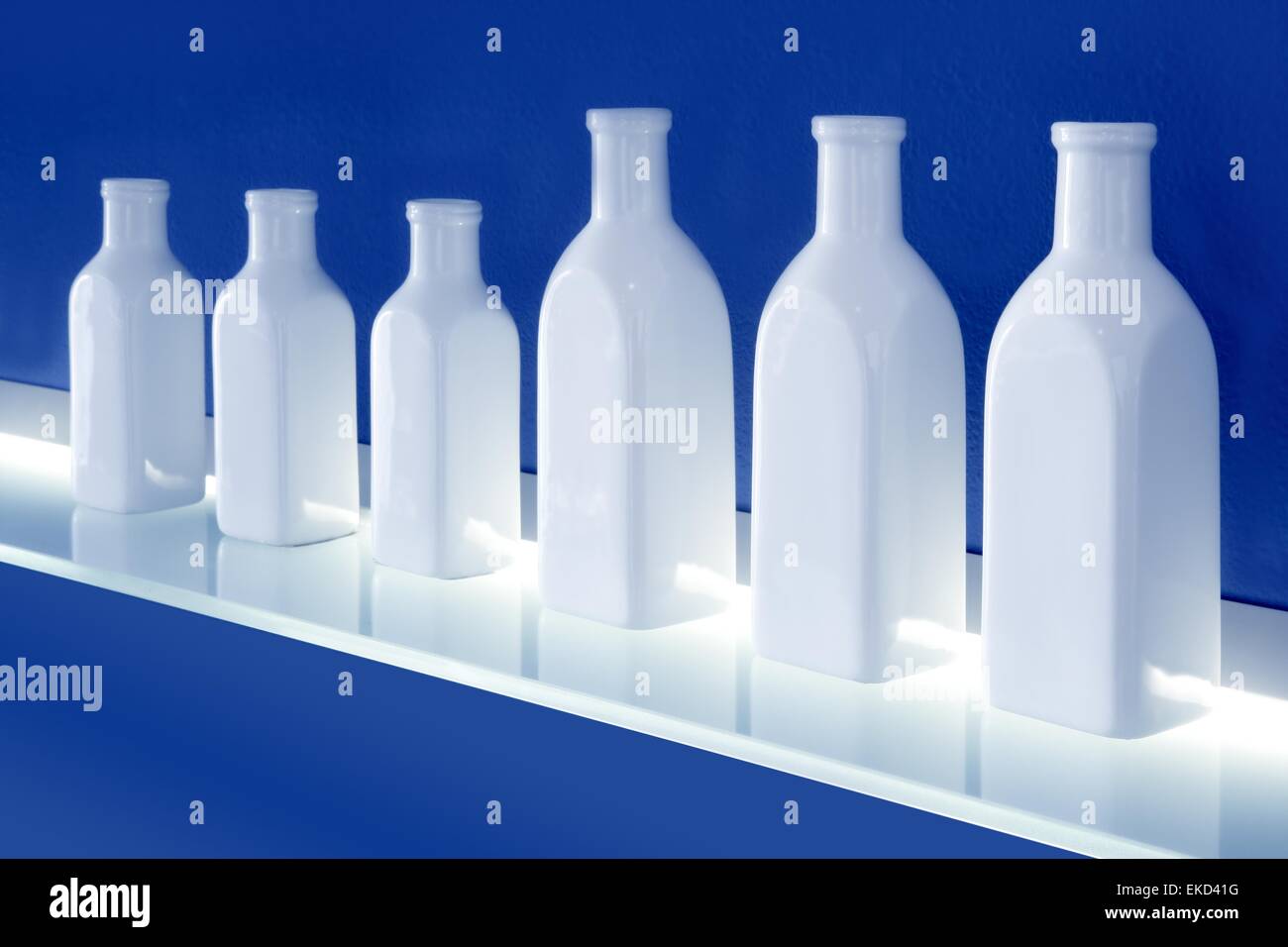 white bottles row on blue background shelf Stock Photo - Alamy