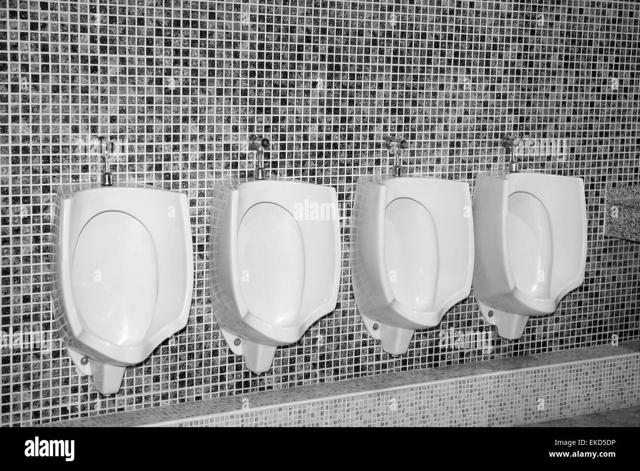 Bathroom urinal in a row with gray tiles Stock Photo - Alamy