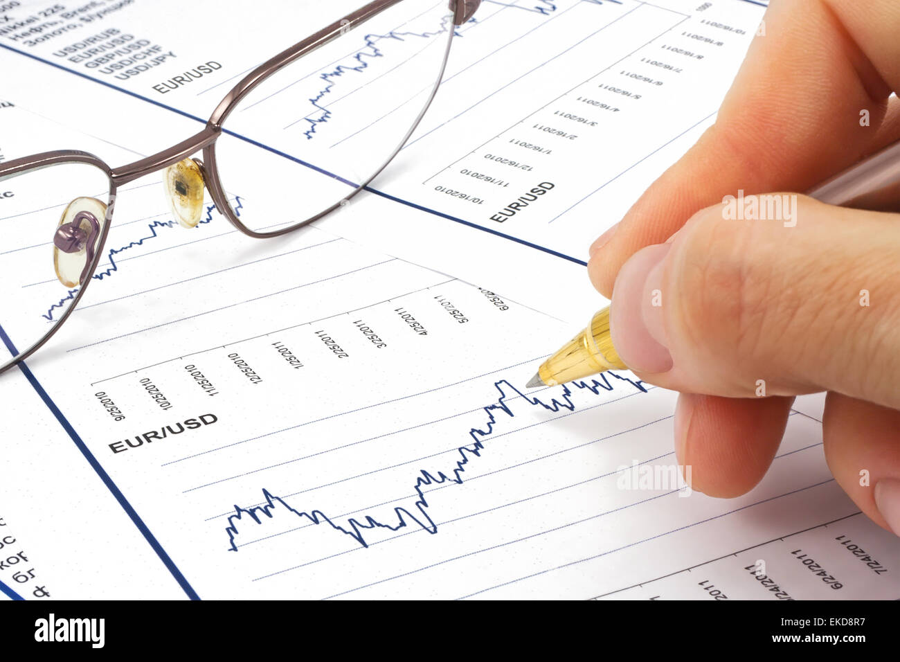 Hand holding pen on a financial report Stock Photo - Alamy