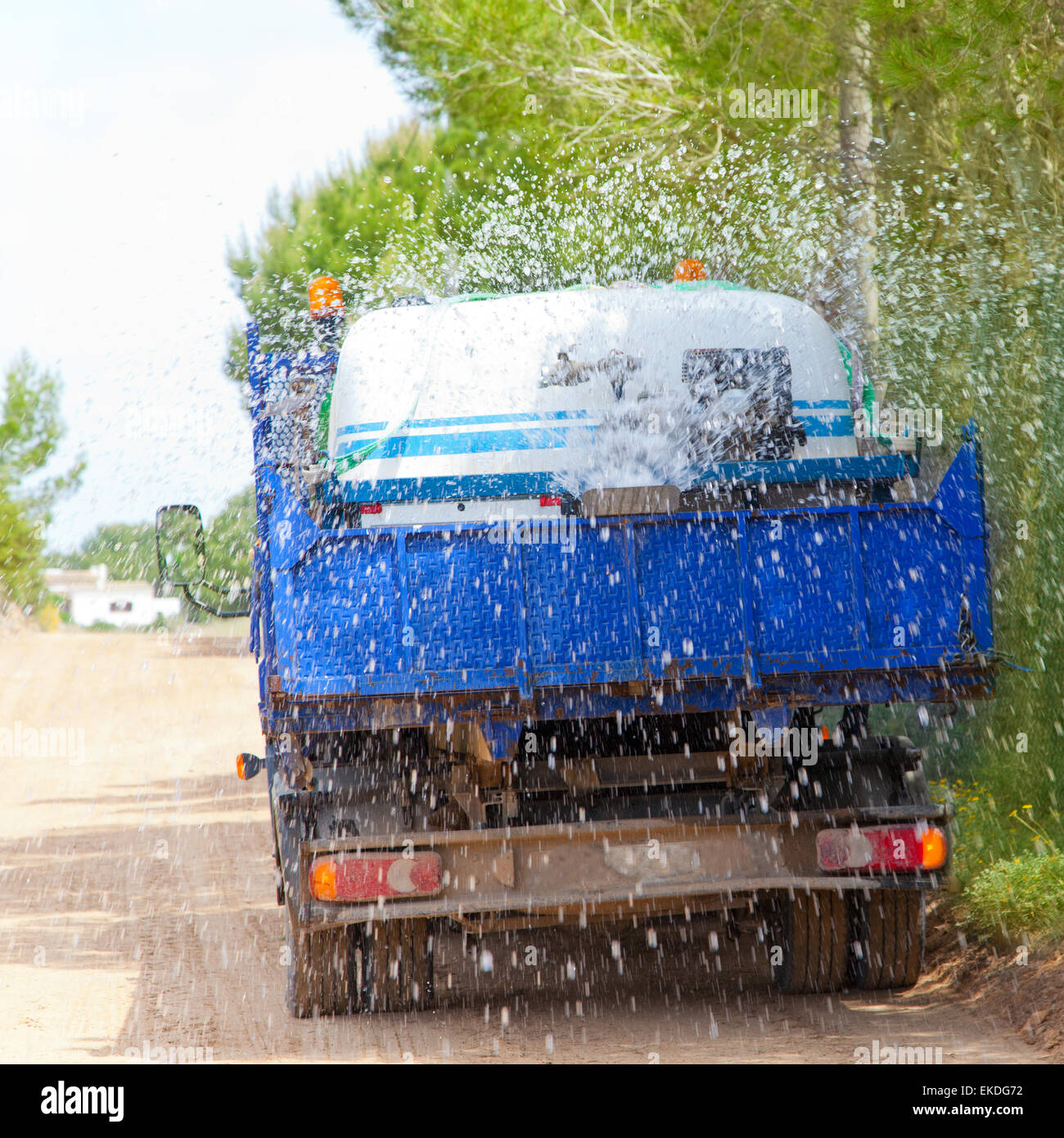 Lorry truck spreading sprinkle water on sand road Stock Photo - Alamy