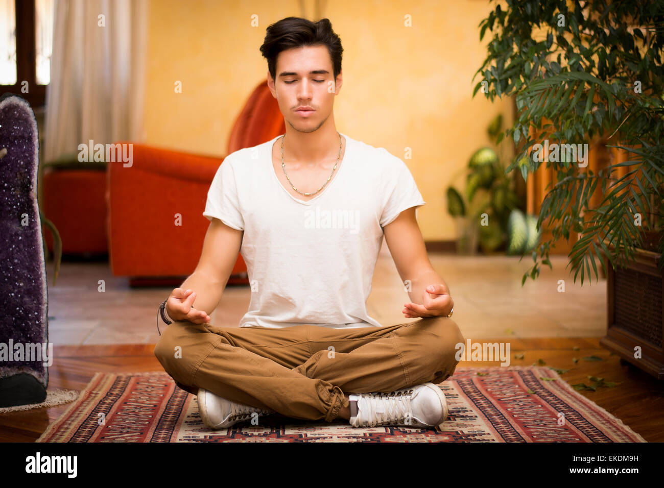 Young man meditating on his living room floor Stock Photo - Alamy