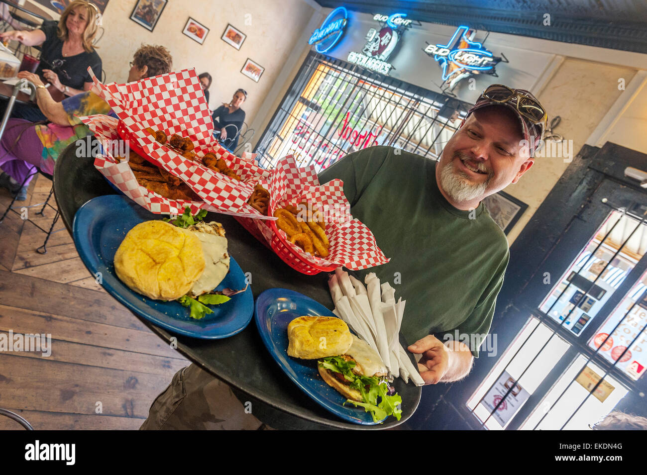 A smiling waiter carrying a tray of burgers and sandwiches at the ...