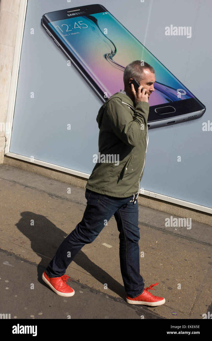 Phone user walks past Samsung shop window ad for new S6 model Stock ...