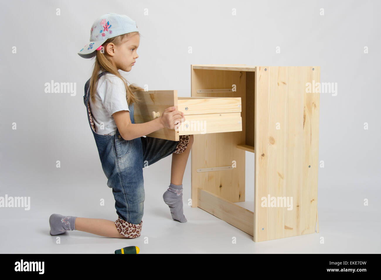 Little girl - furniture collector tries to insert a box in a wooden ...
