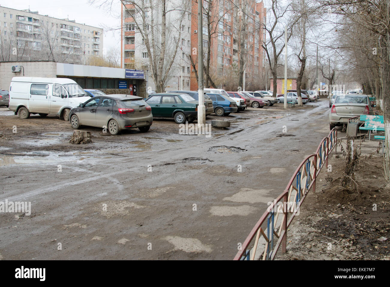 Roadway in the yard with holes in the broken asphalt, mud and puddles ...