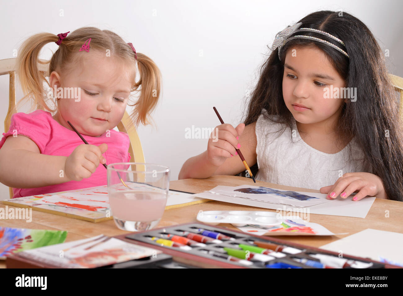 Two girls painting at a table Stock Photo - Alamy